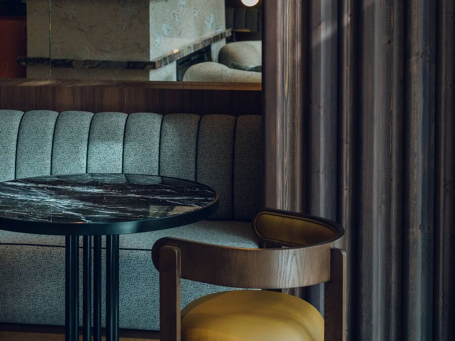 Um interior moderno com uma mesa redonda, uma cadeira de madeira e um sofá.