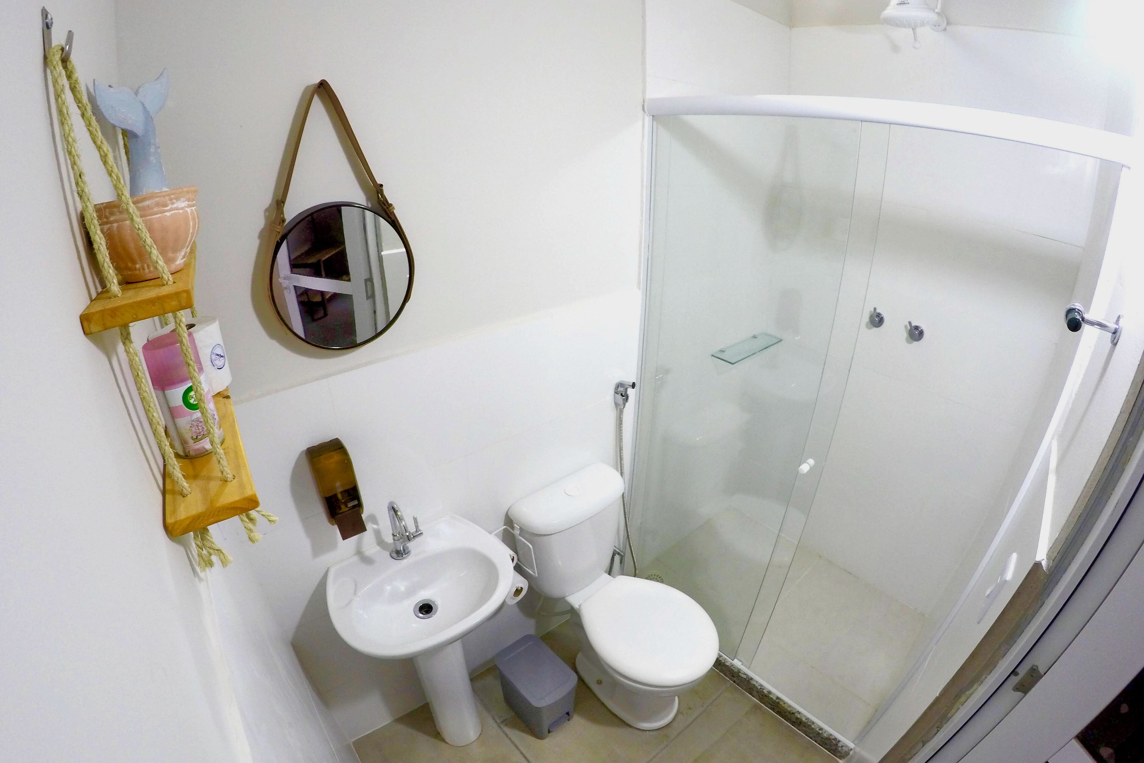 Casa de banho com lavatório, sanita e cabine de duche com vidro.