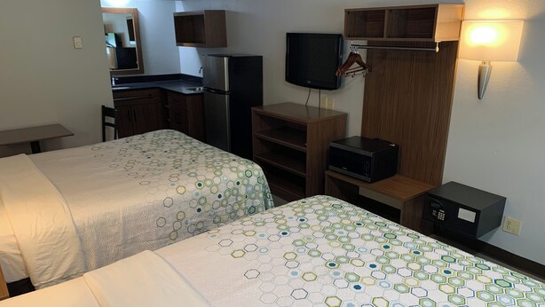 Quarto de hotel com duas camas, televisão, micro-ondas e uma pequena cozinha.