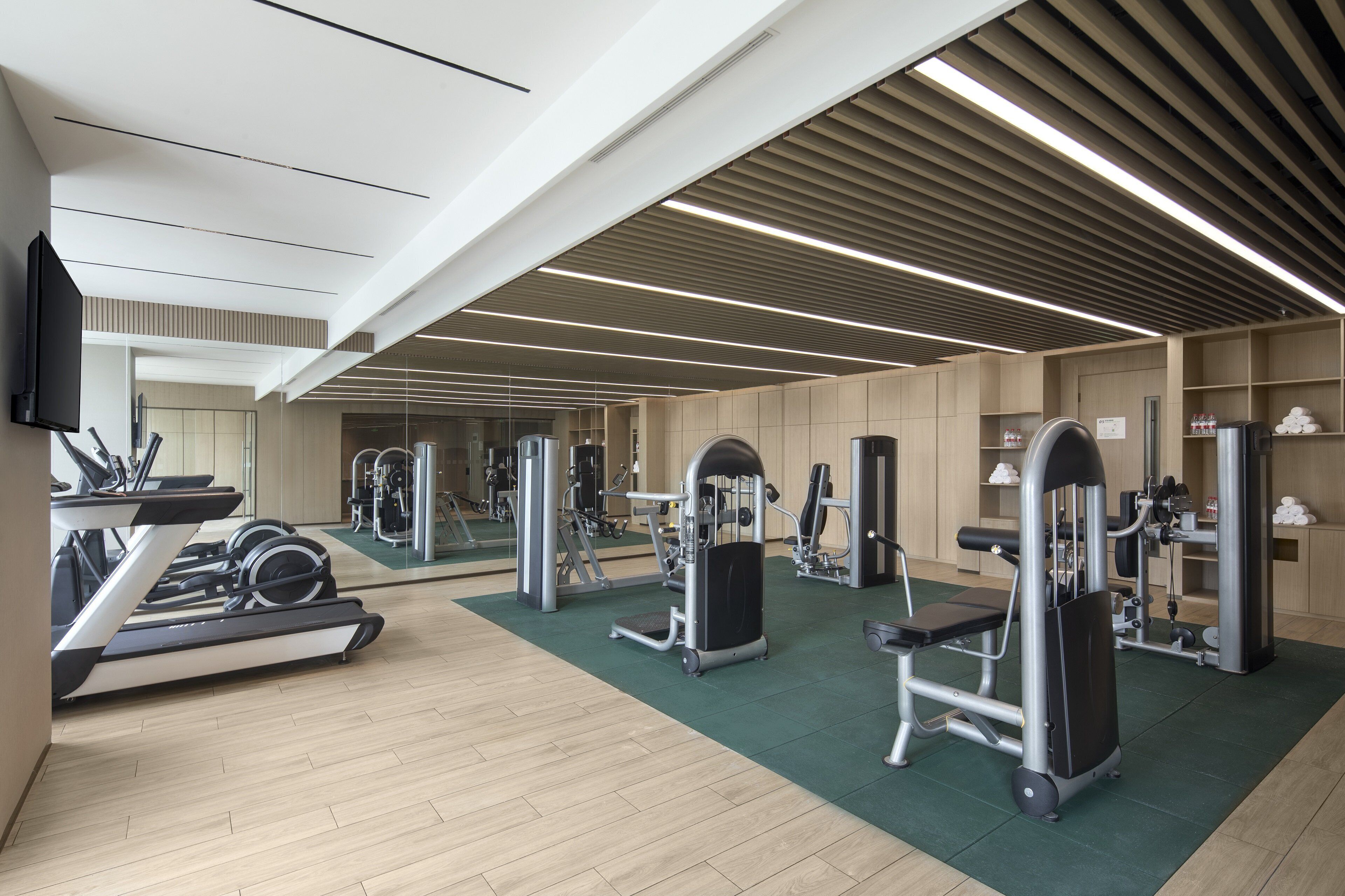 Uma academia com esteiras, máquinas de musculação e espelhos.