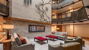 Um hall amplo com parede de destaque em pedra, um quadro grande e uma escadaria para um andar superior.