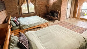 Quarto rústico com uma cama grande, um banco de madeira, um ventilador de teto e uma parede de tijolos.