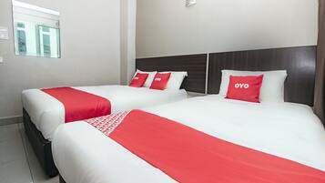 Quarto de hotel com duas camas, cada uma com roupa de cama branca e vermelha, e uma janela com persianas.