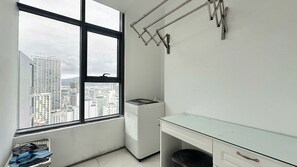 Quarto com uma janela grande, uma escrivaninha branca e um pequeno aquecedor.