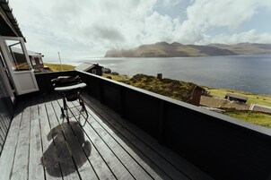 Um deck de madeira com vista para o mar e colinas.