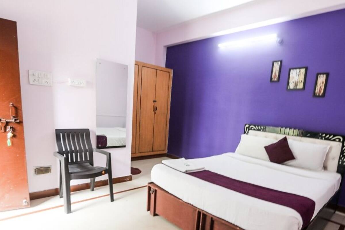 Quarto com cama, uma cadeira, guarda-roupa e porta.