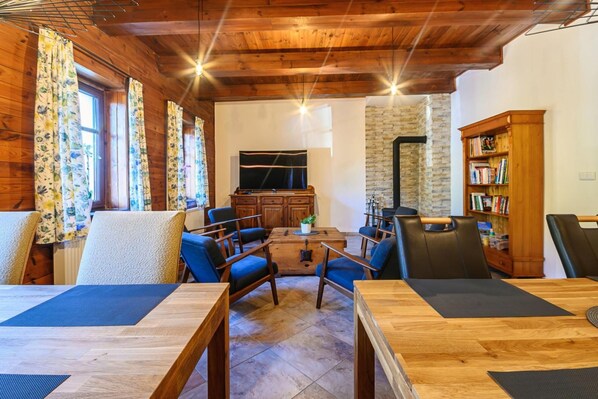 Um quarto acolhedor com paredes de madeira, lareira de pedra, estante de madeira e uma grande televisão de tela plana.