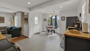 Uma sala de estar ampla com sofá, uma mesa de jantar com cadeiras e uma cozinha com pia e bancada.