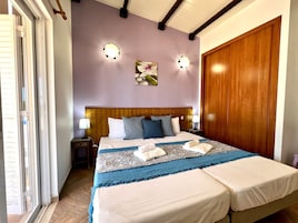 Quarto com cabeceira de madeira, duas mesas de cabeceira com luminárias, uma cama grande com várias almofadas e um guarda-roupa de madeira.