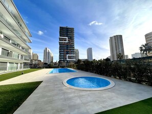 Um complexo residencial moderno com piscina e gramado bem cuidado.