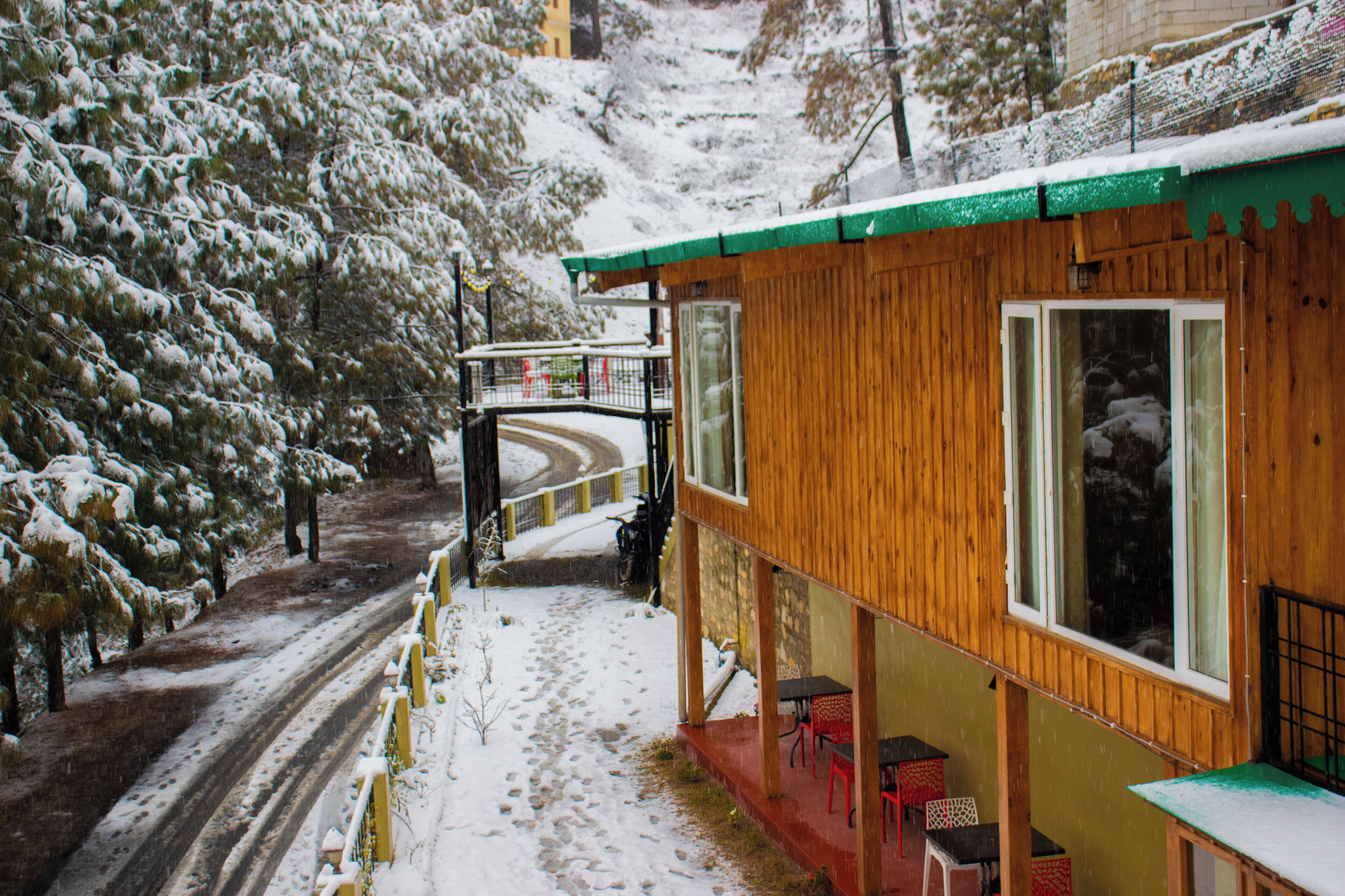 Uma cabana de madeira com varanda coberta, um espaço de estar ao ar livre e vista para uma paisagem coberta de neve.