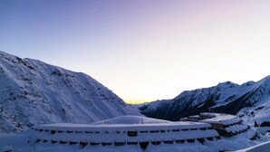 Paisagem montanhosa coberta de neve com uma estrutura de construção circular.