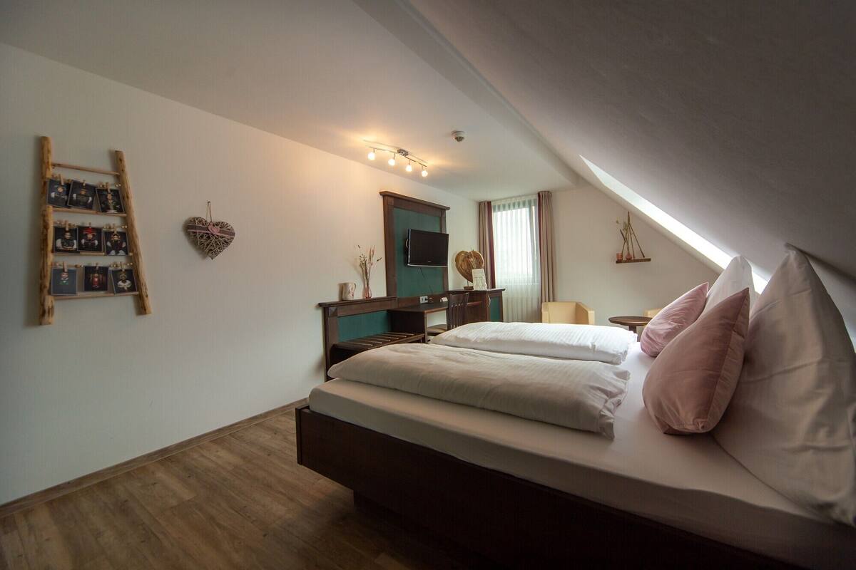 Quarto com beliche, escrivaninha, cadeira, televisão e decoração em formato de coração na parede.