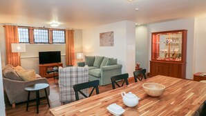 Uma sala de estar com sofá, televisão e um espaço de jantar com mesa e cadeiras.