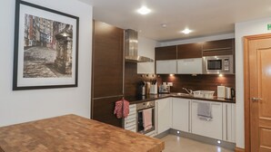 Cozinha moderna com armários de madeira, micro-ondas de aço inoxidável e painel de azulejos.