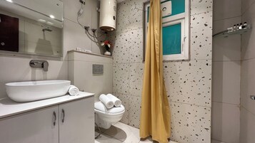 Uma casa de banho com uma sanita, uma pia branca, chuveiro com cortina amarela e um espelho sobre a pia.