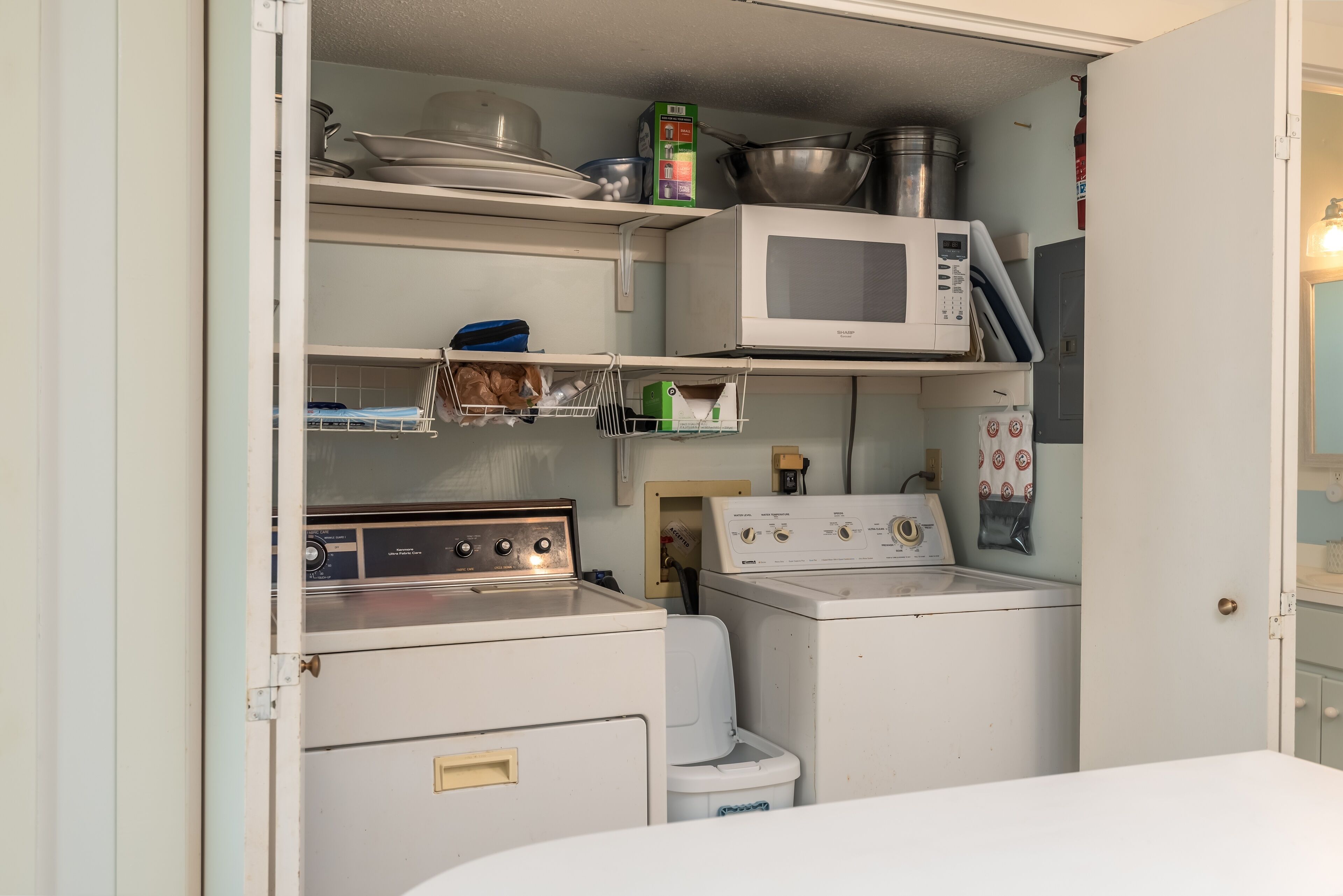 Cozinha compacta com micro-ondas, fogão e máquina de lavar.
