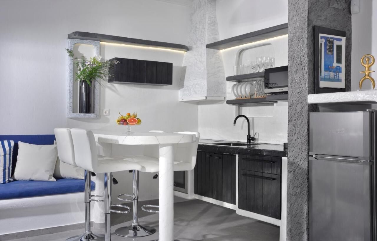 Uma cozinha moderna com mesa de jantar branca, armários pretos e geladeira de aço inoxidável.