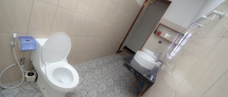Casa de banho com sanita, lavatório e chuveiro.