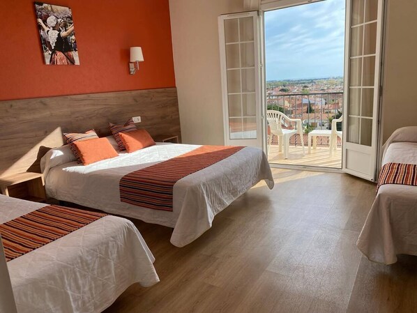 Quarto de hotel com duas camas, varanda e vista, além de piso de madeira.