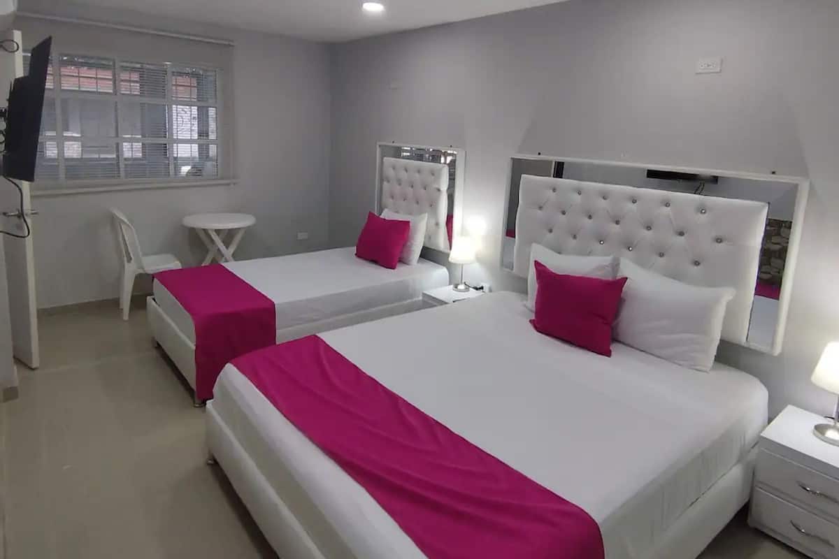 Quarto de hotel com duas camas, uma escrivaninha e uma cadeira.