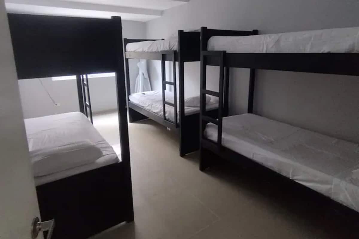 Quarto de dormitório com beliches, janela e porta.