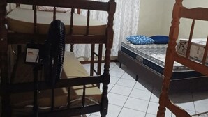Um quarto com duas beliches de madeira, uma mesa pequena e uma cadeira.