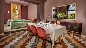 Uma área de jantar com uma mesa posta para quatro pessoas, um sofá verde e um espelho na parede.