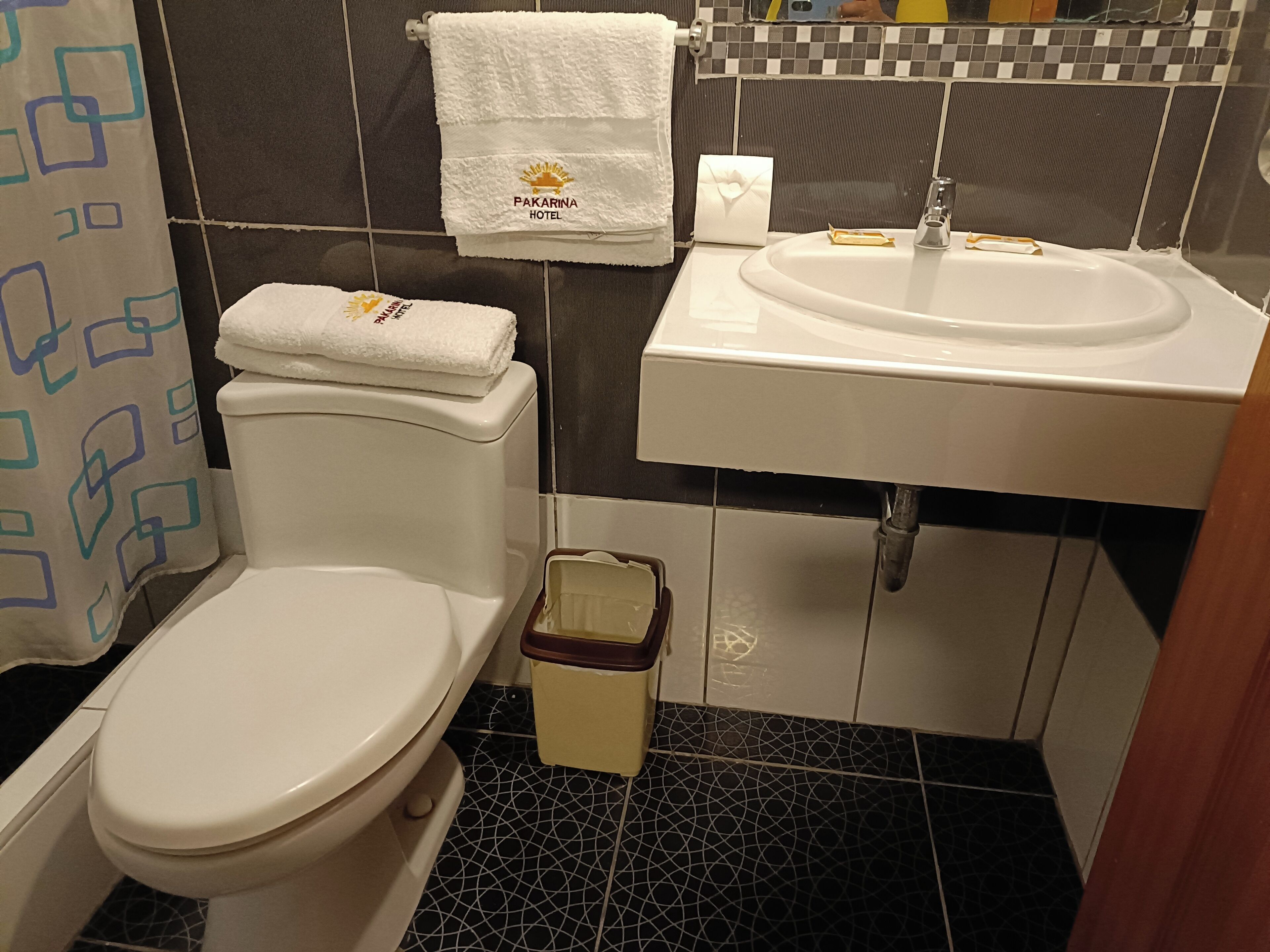 Casa de banho com sanita, lavatório e um contentor de lixo.
