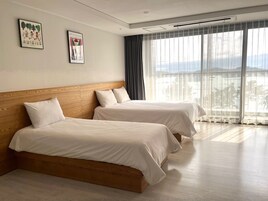Quarto de hotel com duas camas, uma janela grande com cortinas e obras de arte na parede.