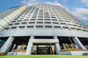 Um hotel moderno com fachada em estilo grade, ampla entrada de vidro e área gramada bem cuidada.