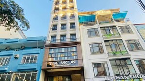 Um hotel com uma placa indicando "The Moon Boutique Hotel" e um restaurante com a placa "HÀS SÁN TUOÏ".