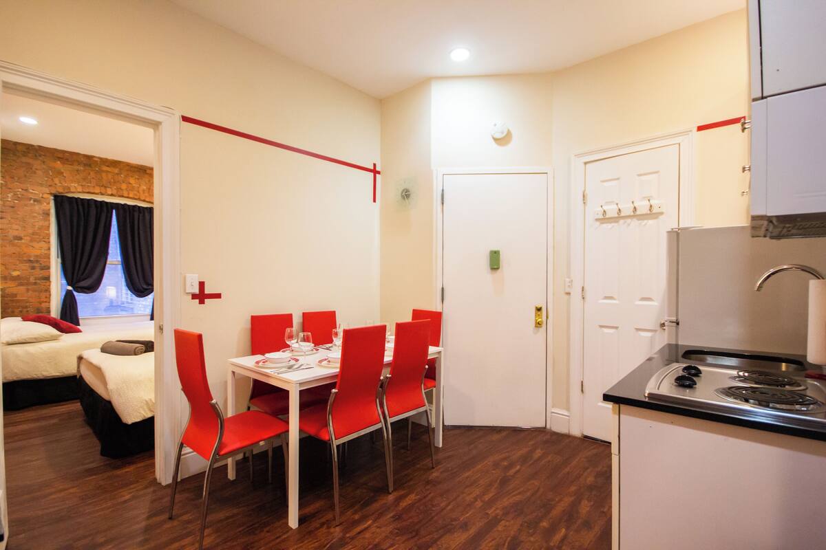 Quarto de hotel compacto com área de refeições, cozinha compacta e quarto separado.