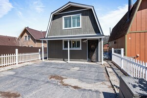 Uma casa de dois andares com varanda da frente, garagem e entrada cercada.