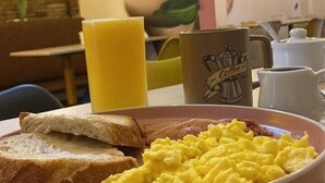 Prato de café da manhã com torradas, ovos mexidos e um copo de suco de laranja.