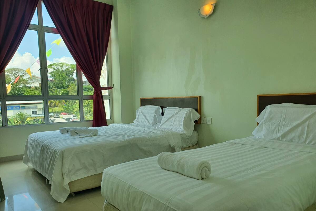 Quarto de hotel com duas camas, uma janela grande com cortinas e vista para o exterior.