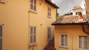 Um edifício amarelo com várias janelas e persianas, telhado de telhas e antena parabólica.