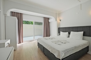 Quarto com cama, guarda-roupa, porta de correr de vidro e luminária fixada na parede.