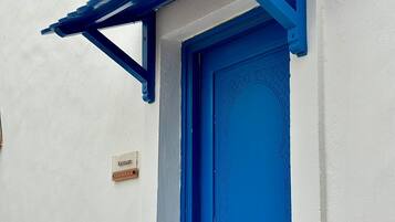 Uma porta azul com parede branca e uma pequena placa acima.