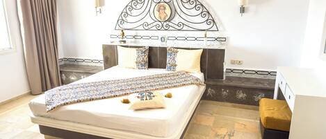 Quarto de hotel com cama, mesa de cabeceira, escrivaninha e cadeira.