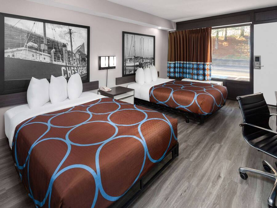 Quarto de hotel com duas camas, uma escrivaninha e uma cadeira.