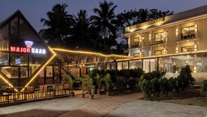 Um hotel com uma placa de destaque para 'The Upper House' e um restaurante visível chamado 'Major Saab' com mesas ao ar livre.