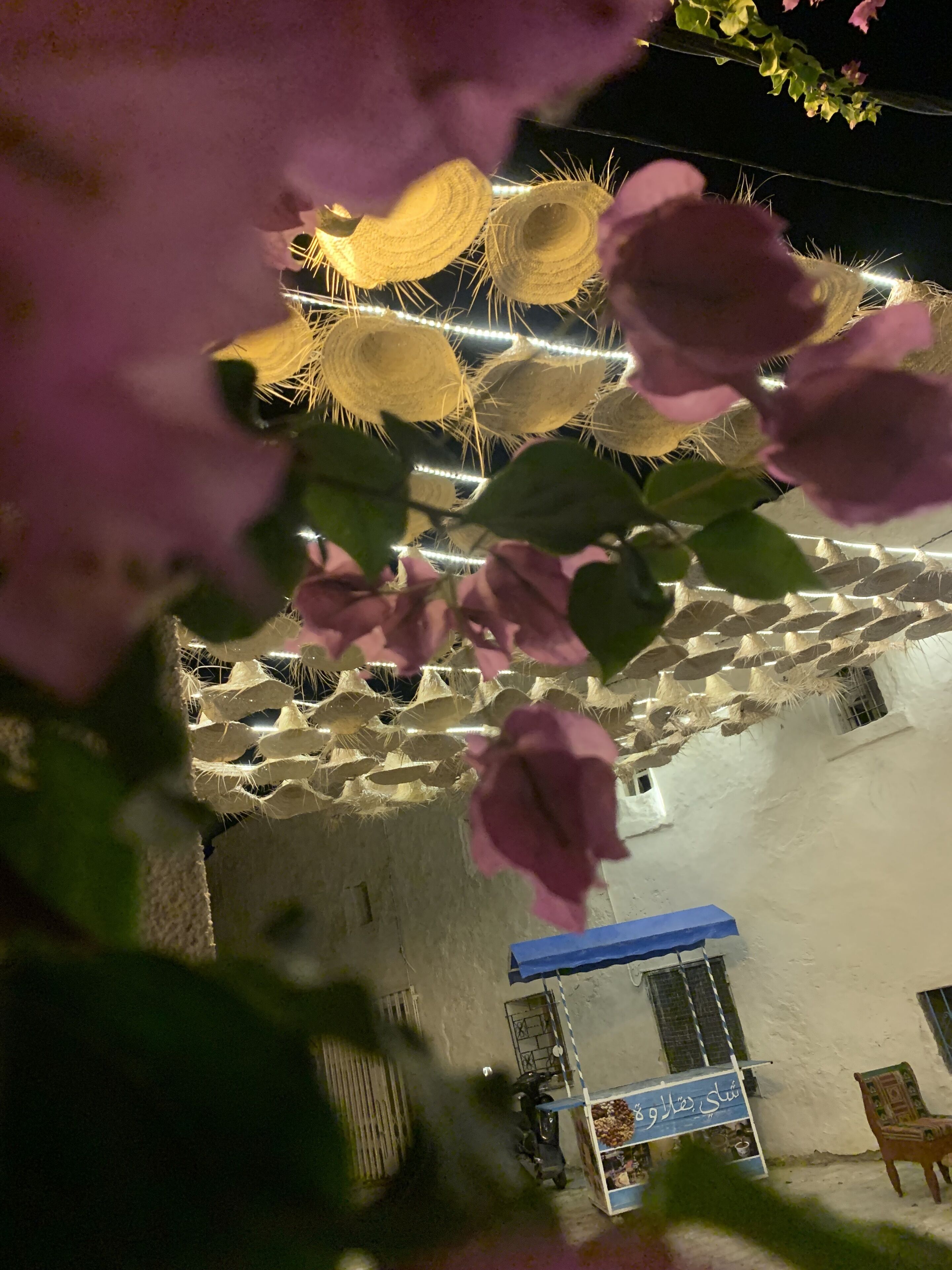 Um edifício tradicional com toldo azul, uma placa com escrita estrangeira e um carrinho de rua.