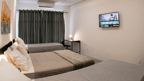 Quarto de hotel com duas camas, uma escrivaninha, televisão e um quadro na parede.