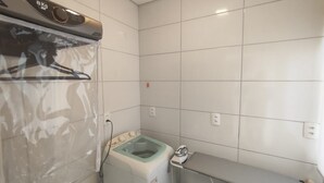 Uma lavanderia compacta com máquina de lavar, varal e aquecedor.
