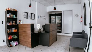 Uma área de recepção com balcão, painel de madeira, refrigerador e espaço para sentar.