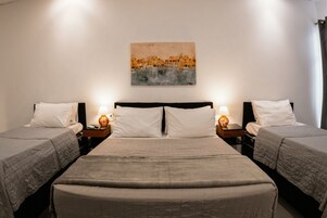Quarto duplo com duas camas, uma mesa de cabeceira com abajur e um quadro na parede.