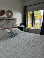 Quarto de hotel com uma cama grande, mesa de cabeceira com cafeteira e vista para o exterior.