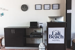 Uma receção com um computador, uma impressora e o letreiro do Hotel Lali Beach.
