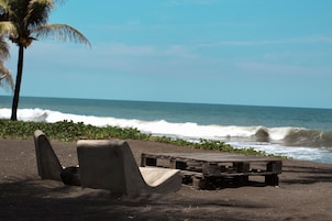 Uma praia com um banco de concreto e uma mesa de piquenique de madeira.
